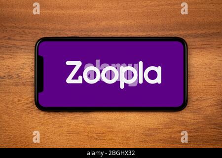 A smartphone showing the Zoopla logo rests on a yellow background along ...