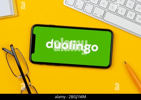 An iPhone showing the Duolingo website rests on a yellow background ...