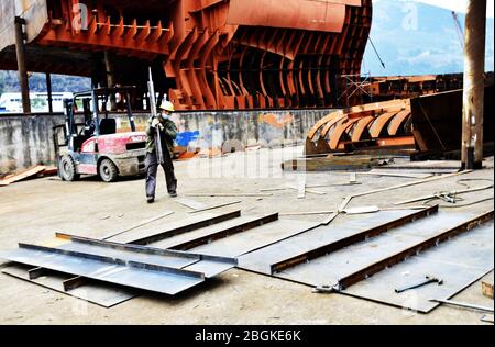 Staff work to produce a large vessel at a ship factory along the ...
