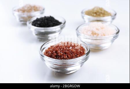 Different sea salt in bowls and scoops isolated on white, top and side ...