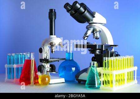 Microscopes and test tubes on table, on color background Stock Photo ...
