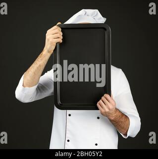 Portrait of chef with oven pan behind his face on dark background Stock ...