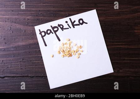 Paprika seeds on piece of paper with ground and rake on wooden ...