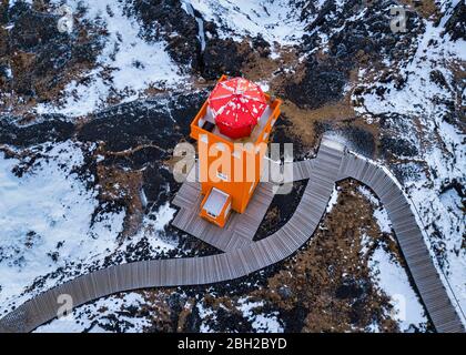 Aerial view of orange Svortuloft Lighthouse by the sea in West Iceland ...