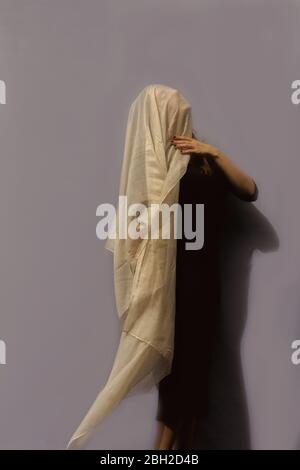 Woman under cloth in front of gray wall Stock Photo - Alamy
