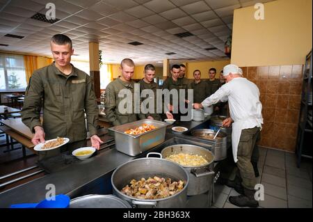 At a chow hall: soldiers stand in front of a serving bar and wait for ...