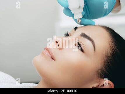 Young woman receiving facial rejuvenation gua sha treatment with rose ...