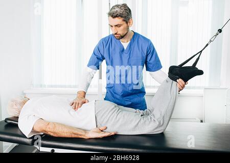 kinesiologist doing therapeutic exercises for an elderly patient ...