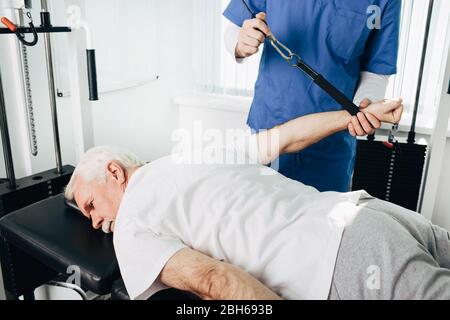 kinesiologist doing therapeutic exercises for an elderly patient ...