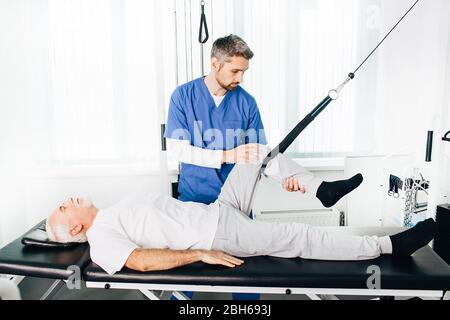 kinesiologist doing therapeutic exercises for an elderly patient ...