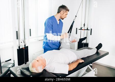 kinesiologist doing therapeutic exercises for an elderly patient ...