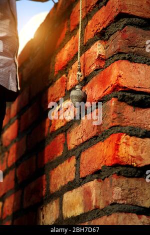 Use of a plumb bob for the construction of a brick wall Stock Photo - Alamy