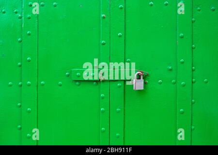 Vibrant green metal doors with big rivets, locked up with a latch and a ...
