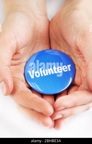 Round volunteer button in hands isolated on white Stock Photo - Alamy