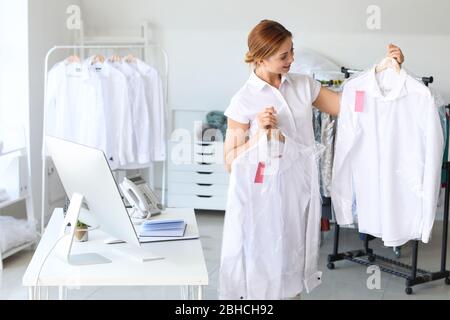 Worker of modern dry-cleaner's at reception Stock Photo - Alamy