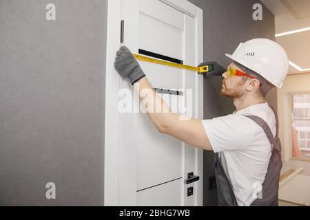 Carpenter worker installation process of measures cloth with ruler door ...