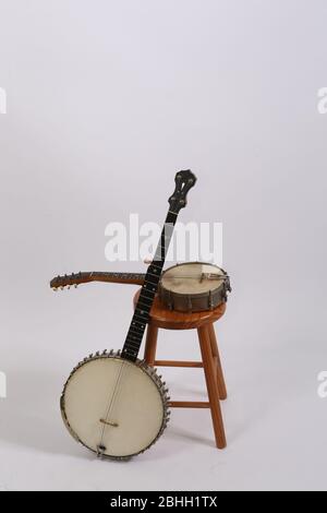 A banjo resting against a stool with a banjalele Stock Photo - Alamy