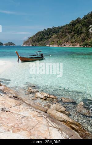 A boat parked in the crystal clear sea with a mountain in the ...