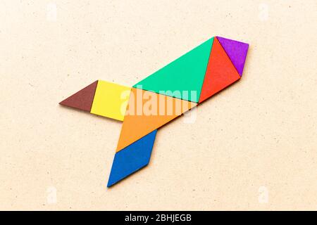 Color tangram puzzle in rocket or missile shape on wood bacground ...
