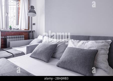 Cozy bedroom interior with grey pillows, white linens, wooden headboard ...