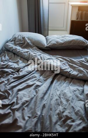 Messy bed with crumpled blankets in a bedroom setting Stock Photo - Alamy