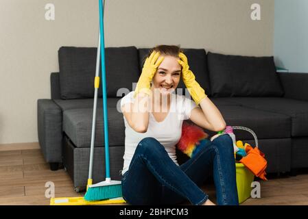 Depressed maid sitting in her bucket and holding her mop, with a sad ...