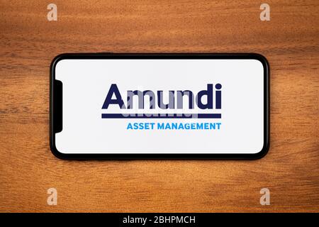 A smartphone showing the Amundi Asset Management logo rests on a yellow ...