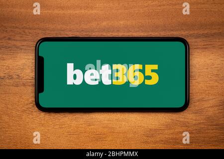 A smartphone showing the Bet365 logo rests on a yellow background along ...