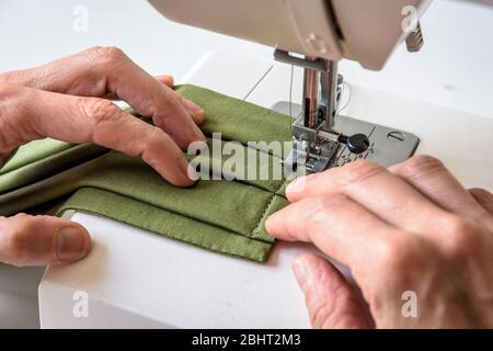 Sewing cotton face mask with a sewing machine for coronavirus outbreak ...
