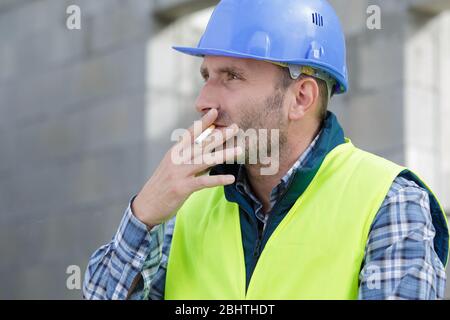 happy builder smoking cigarette on construction site Stock Photo - Alamy