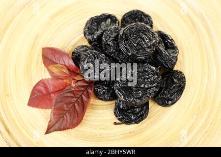 Pile of prunes with leaves on wooden tray, closeup Stock Photo - Alamy
