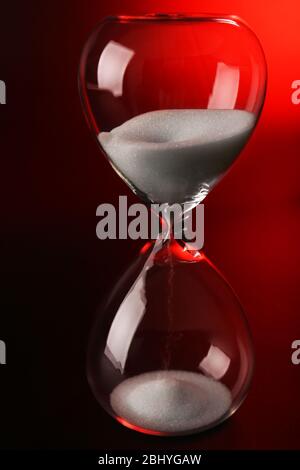 Hourglass on dark red background Stock Photo - Alamy