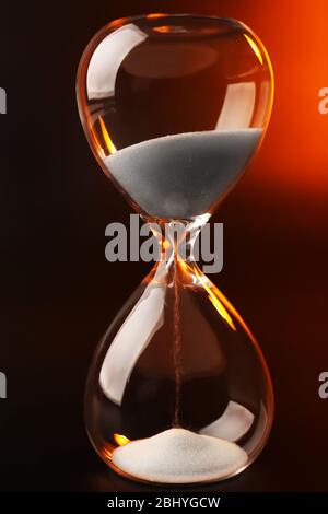 Hourglass on dark color background Stock Photo - Alamy