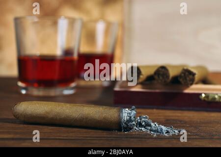 Cigars and burnt one with ash and cognac on wooden table, closeup Stock ...