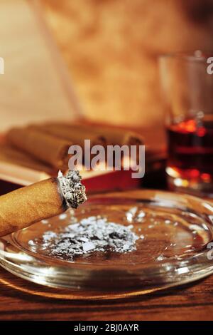 Cigars and burnt one with ash and cognac on wooden table, closeup Stock ...