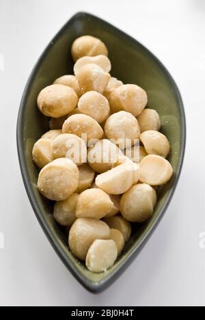 Macadamia nuts, roasted and salted, in a wooden bowl on linen fabric ...