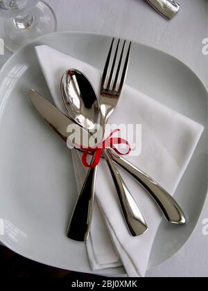 cutlery tied with red ribbon on set of plates Stock Photo - Alamy