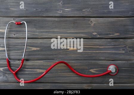 red stethoscope on dark brown wooden background Stock Photo - Alamy