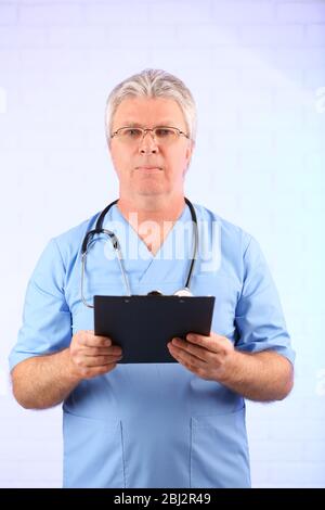Doctor with clipboard on light blue background Stock Photo - Alamy