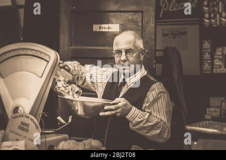 Sepia front view of 1940s man as vintage shopkeeper, grocer, in WW2 ...