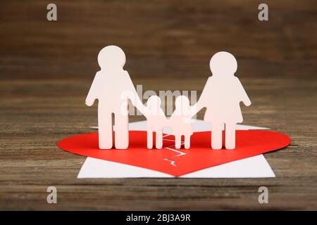 Paper cutout silhouette of a family split apart on a paper heart ...