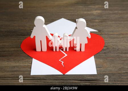 Paper cutout silhouette of a family split apart on a paper heart ...