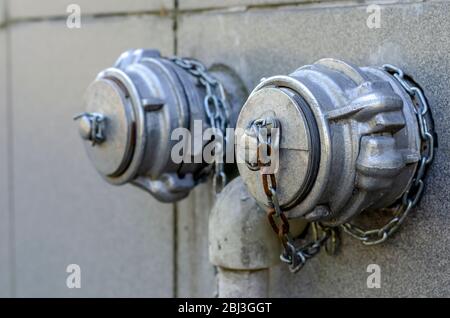 Aluminum fire hydrants in the wall with covers on chains. Two fire ...