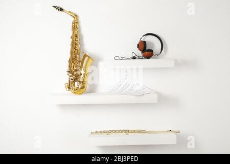Musical instruments and headphones on decorated shelves against white ...