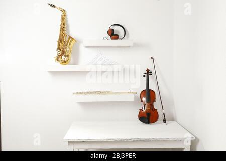 Musical instruments and headphones on decorated shelves against white ...