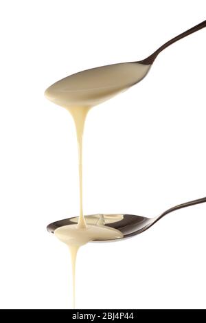 Condensed milk pouring from spoons, isolated on white Stock Photo - Alamy