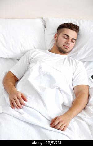 Beautiful young man snoozing on bed Stock Photo - Alamy