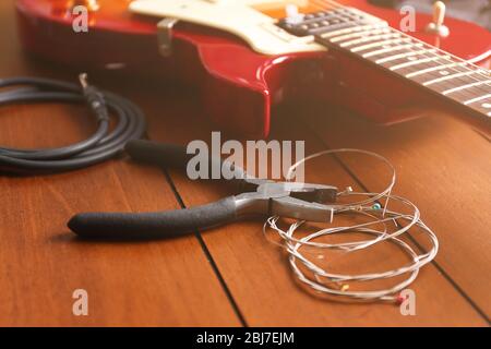 Electric guitar with pliers and strings on wooden background Stock ...