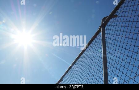 Cyclone fence with sun flare Stock Photo - Alamy