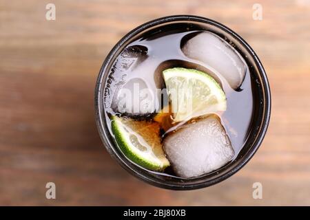 Cocktail with lime slices and ice blocks on wooden table, top view ...